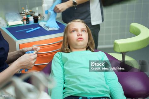 치과 의사 사무실의 의자에 앉아있는 작은 무서운 소녀 아이 발치 치아 치료를 두려워하는 아이는 입을 벌리고 검사합니다 치과 검진 뒤로 젖힌 자세 치과 용 장갑 6 7 살에