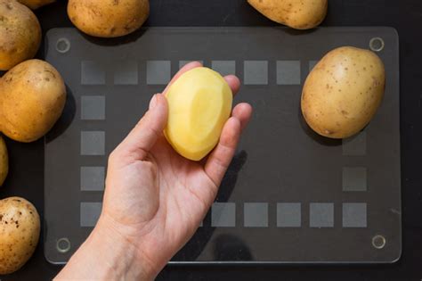 검은 배경에 하나의 원시 껍질을 벗긴 감자를 들고 여자의 손의 상단보기 감자 요리에 대한 스톡 사진 및 기타 이미지 감자 요리 건강한 생활방식 건강한 식생활 Istock