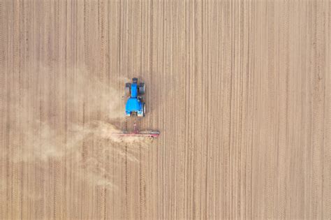 파란 트랙터 쟁기를 당겨 종자 파 종 트랙터를 만드는 흙 구름을 위한 토양을 준비 하는 공중 하향식 보기 계절에 대한 스톡 사진