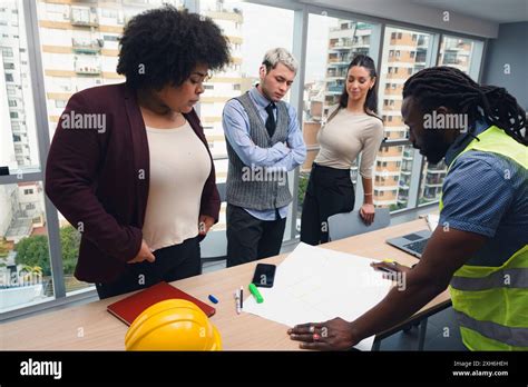 Engineer Man With Dreadlocks Is Explaining Plans Of Work In Board