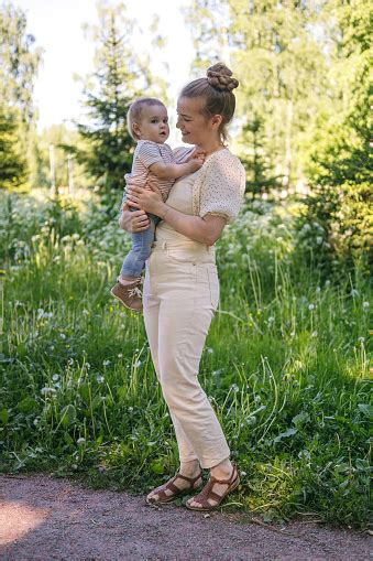 한 젊은 어머니가 한 살 짜리 아기와 함께 걷고 그를 품에 안고 안고 있다 그의 조화로운 발전을위한 아이와의 의사 소통 12 17 개월에 대한 스톡 사진 및 기타 이미지