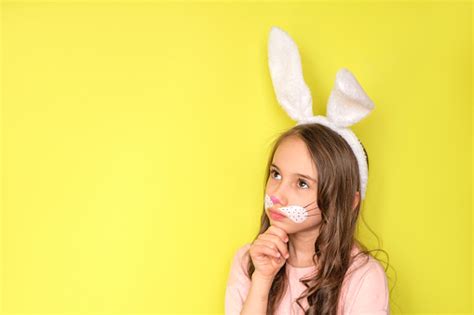 슬프고 사려 깊은 소녀는 복사 공간의 노란색 스튜디오 배경에 부활절 토끼 귀가 달린 얼굴을 그렸습니다 8 9 살에 대한 스톡 사진 및 기타 이미지 Istock