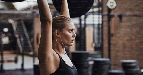 체육관에서 운동하는 동안 머리 위로 무거운 바벨을 들고 운동복을 입은 젊은 금발 여성에게 적합 사진 Unsplash의 체육관 이미지