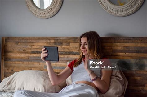 무선 태블릿을 사용하여 침대에 앉아 화상 채팅을 통해 누군가와 이야기하는 어린 십대 소녀 가정 생활에 대한 스톡 사진 및 기타 이미지 가정 생활 가정의 방 긍정적인