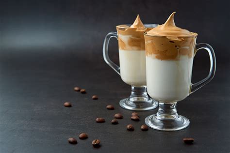 트렌디한 푹신한 크림 달고나의 안경 또는 어두운 배경에 우유와 커피 콩을 곁들인 인스턴트 커피 새로운 인기 있는 음식 및 음료 트렌드 컨셉 복사 공간â 0명에 대한 스톡