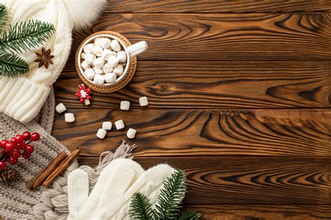 크리스마스 개념 모자 니트 스카프 장갑 전나무 가지 컵 코코아와 마시멜로 등나무 Placemat 겨우살이 열매와 계피 스틱의 상단보기 사진 카피 스페이스가있는 나무 책상