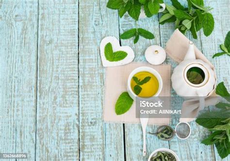 나무 소박한 테이블에 흰색 찻잔에 신선한 녹색 민트 잎과 민트 차 건강한 상쾌한 음료 식물 요법 약용 허브 주전자를 곁들인 허브