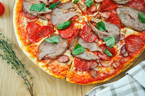 나무 테이블에 고기 살라미 고추를 곁들인 이탈리아식 홈메이드 피자 복사 공간이있는 상단보기 음식 플랫 레이 건강에 좋지 않은