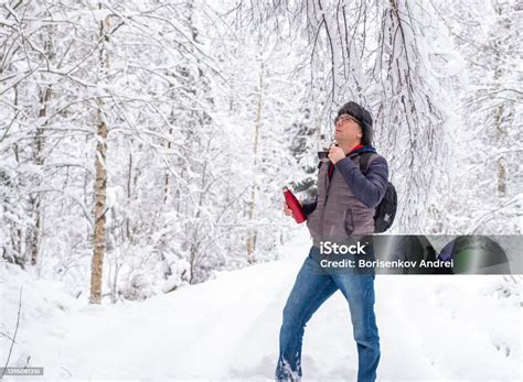 겨울 옷을 입고 커피 한 잔을 들고 백인인 한 남자가 눈 덮인 숲에 서 있다 남자는 쉬고 조용히 즐기고 있다 40 49세에 대한 스톡 사진 및 기타 이미지 Istock