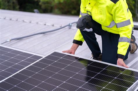 기술자가 설치 중 태양광 패널을 들어 올리고 재생 에너지 발전을 보여주고 있습니다 안전 장비를 착용하고 녹색 에너지 솔루션과 지속 가능한 개발에 중점을 둡니다 건설 기계류에