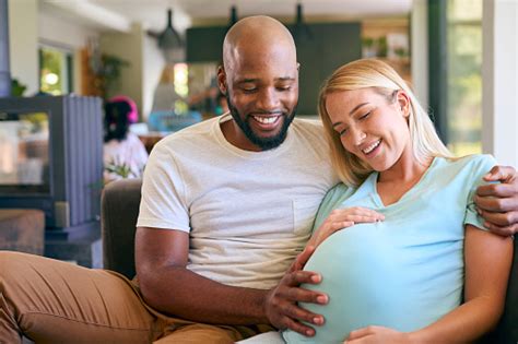 다세대 가족과 함께 집에서 소파에 앉아 있는 임신한 여성과 사랑하는 다인종 커플 20 29세에 대한 스톡 사진 및 기타 이미지