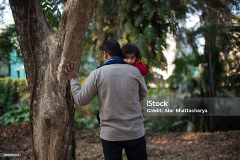 인도의 갈색 머리 아버지와 겨울 옷을 입은 그의 아기 소년은 숲 배경의 마른 잔디 밭에서 겨울 오후에 자신을 즐기고 있습니다 2 3 살에 대한 스톡 사진 및 기타 이미지