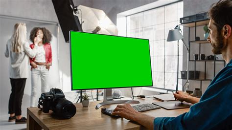 사진 촬영의 백스테이지 메이크업 아티스트가 아름다운 흑인 소녀에게 메이크업을 적용합니다 사진 편집기 녹색 모형 화면 디스플레이와 데스크톱 컴퓨터에서 작동합니다 패션 인터넷