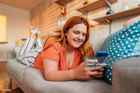 집에서 스마트 폰으로 소셜 미디어를 확인하는 젊은 여성 과체중에 대한 스톡 사진 및 기타 이미지 과체중 소파 한 명의