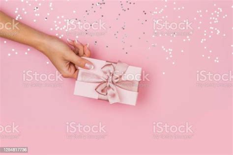 분홍색 파스텔 테이블 상단보기에 색종이로 장식 된 선물 이나 선물 상자를 들고 있는 여성 손 생일 이나 결혼식을 위한 플랫 구성