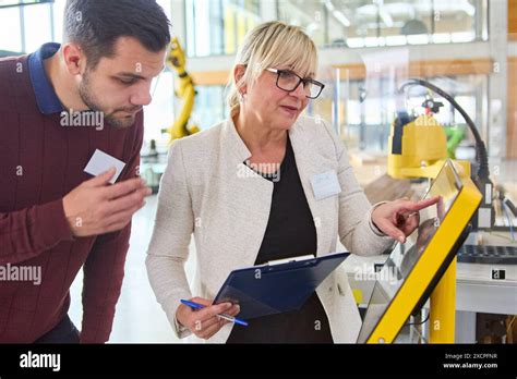 Two Engineers Reviewing An Automation Process In A Robotics Lab Using A Touchscreen Interface