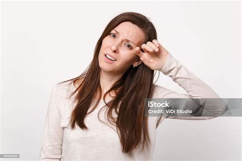 스튜디오에서 흰색 벽 배경에 고립 된 손으로 눈물을 닦아 가벼운 옷을 입고 젊은 여자 울고 불쾌 한 화가의 초상화 사람들은 진심으로 감정 라이프 스타일 개념입니다 복사