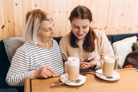 Two Women Sitting In A Cafe Talking And Drinking Coffee Female