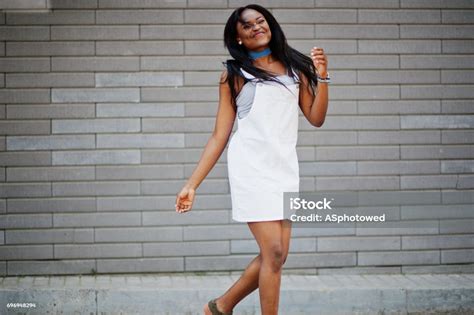 백그라운드에서 벽돌 벽에 선글라스와 함께 포즈를 취하는 사랑 스러운 젊은 아프리카계 미국인 여자의 초상화 가방에 대한 스톡 사진