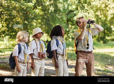 Group Of Scouts In Forest Exploring Nature With Adult Scout Leader Looking In Binoculars Stock