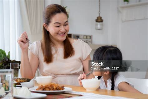 행복 아시아 가족 어머니와 딸은 집에서 함께 부엌에서 음식을 먹고 부모와 아이는 거실에 앉아 식사를하고 유대감과 관계 라이프 스타일과 영양 개념을 가지고 있습니다 2명에