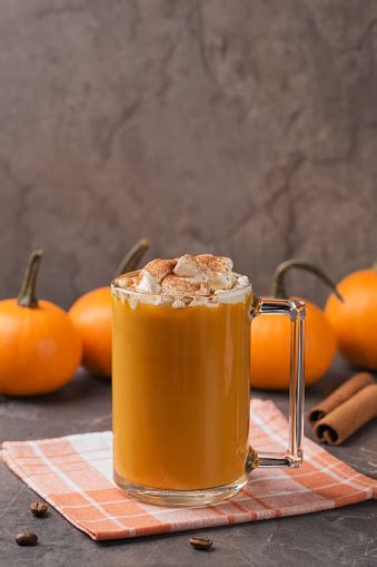 가을 호박 향신료 라떼와 머그잔에 크림을 넣고 어두운 테이블에 미니 호박을 곁들입니다 가을 휴가를위한 전통적인 커피 음료 미니 호박으로 장식 된 테이블 가을 시간 수직 방향