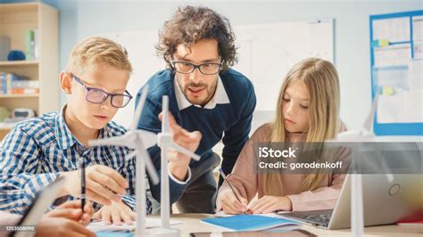 초등학교 교실 태블릿 컴퓨터를 들고 열정적인 교사가 훌륭한 어린 아이들에게 교훈을 설명합니다 프로그래밍 언어 인터넷 안전 및 정보 기술을 학습하는 어린이 개발에 대한 스톡