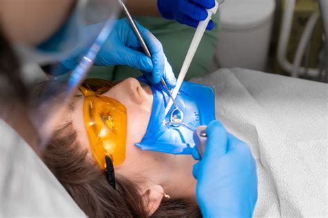 치과 의사 여성은 병원에서 젊은 여성 환자의 치아를 치료합니다 치과 의사는 치과 드릴을 사용하고 치아를 연마 할 때 안면 마스크를 착용합니다 현대 치과 의사 사무실의 치과