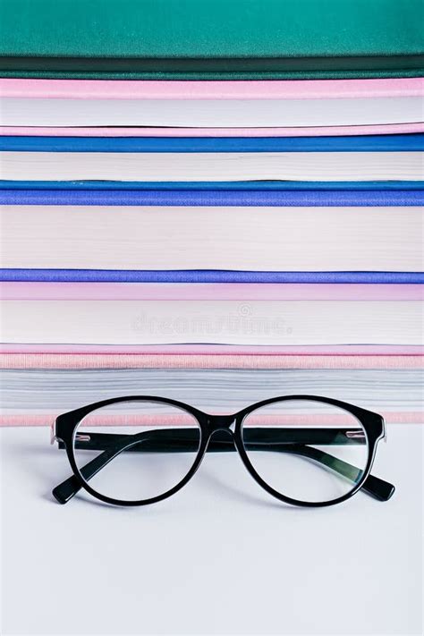 Stack Of Books On Bookshelf With Reading Glasses Against Pink Wall