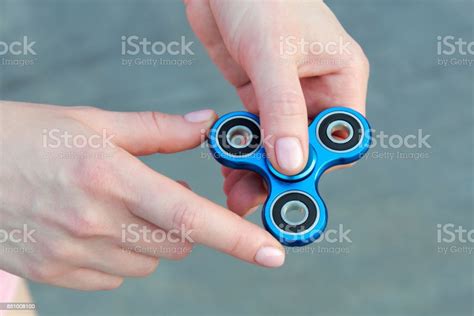회색 배경 스트레스와 이완 Fidgets 안티 불안 구제 장난감 인기 있는 피 젯 회전자 장난감을 들고 거리 여성 손에 손에 파란 금속 회전자를 재생 하는 여자 경감에 대한