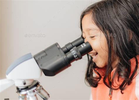 Diverse Pre Babe Girl At Home During Summer Break Exploring Science Looking Through Microscope