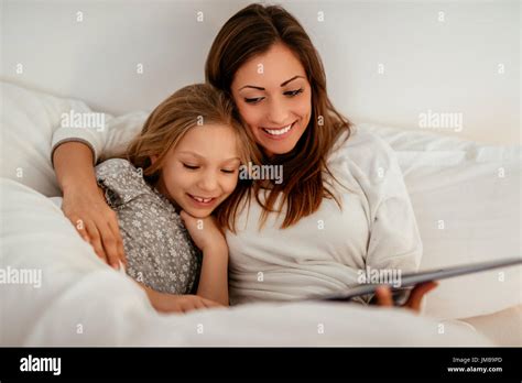 Schöne Lächelnde Mutter Und Ihre Tochter Lesen Im Bett Zu Buchen