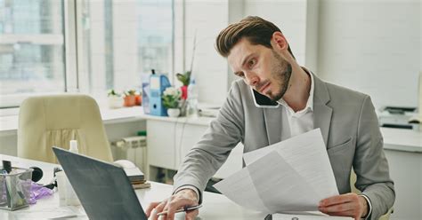 정장을 입은 바쁜 젊은 회사원이 휴대폰 전화기로 고객을 컨설팅하는 동안 노트북 디스플레이의 데이터를 보고 금융 서류를 읽는다 사진 Unsplash의 사무실 이미지