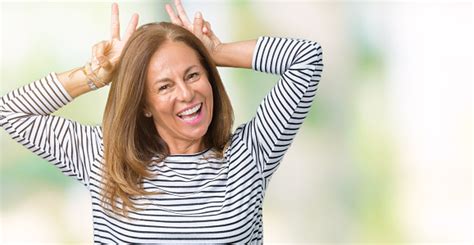 아름 다운 중 년 여 자가 입고 줄무늬 스웨터 토끼 귀 재 밌 고 머리에 손가락으로 미친 체 고립 된 배경 위에 밝은 미소 가을에 대한 스톡 사진 및 기타 이미지 Istock