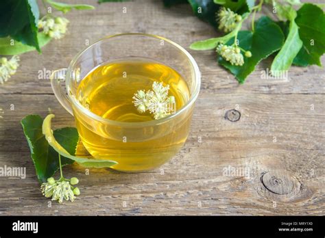 Healthy herbal linden tea with bunch of fresh linden flowers on wooden ...