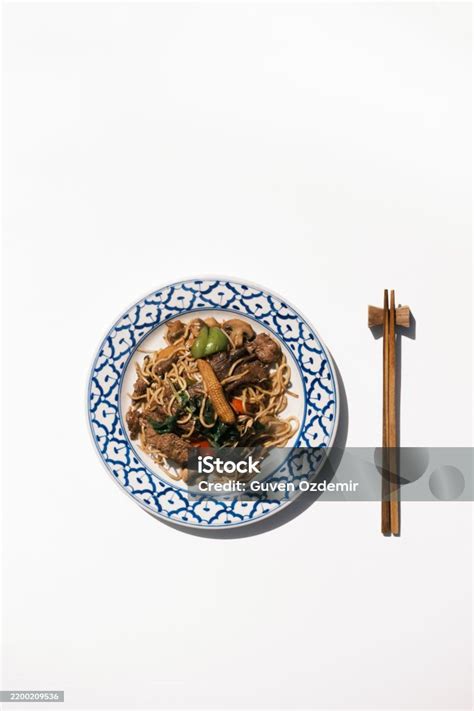 쇠고기와 야채를 곁들인 태국식 계란 볶음 국수의 평면도 흰색 배경에 나무 젓가락이 있는 전통적인 파란색과 흰색 도자기 접시에 제공 정통 태국 요리 0명에 대한 스톡 사진 및