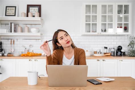 Asian Young Woman Seriously Working On Computer Laptop In House Stock