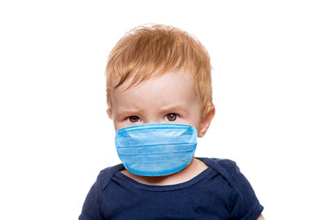 금발 머리를 한 눈으로 가늘게 뜨고 있는 의료용 마스크를 쓴 유아 흰 피부의 소년은 하얀 배경에 고립된 얼굴에 감정을 가진 아이의 초상화를 프레임안으로 들여다본다 감정에