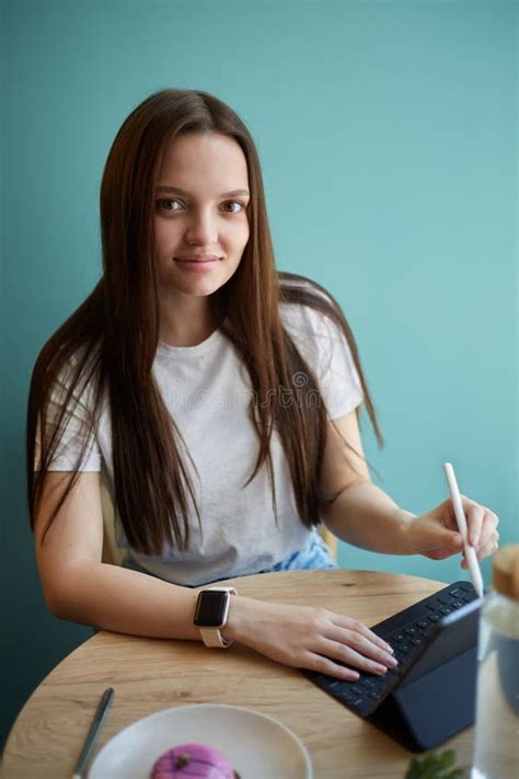Beautiful Young Woman Drawing A Sketch With A Stylus Pen On A Tablet Computer In A Cafe