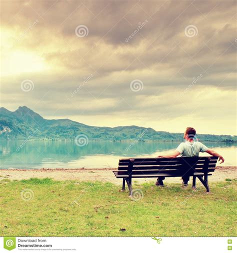 Один человек сидит на стенде около лазурного озера горы человек ослабляет Стоковое Изображение