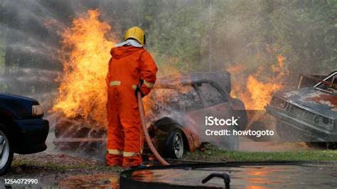 소방관은 화재 호스 화학 물 거품 스프레이 엔진을 사용하여 화염과 싸우고 소방관은 하드 모자 보호를위한 바디 안전 정장 유니폼을 착용합니다 소방 소화기 구조 훈련 불에 대한