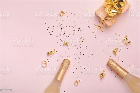 샴페인 병 선물 또는 선물 상자와 분홍색 배경에 황금 빛나는 반짝반짝 반짝반짝 빛나는 스타 색종이 크리스마스 또는 새해 구성 또는 카드 축하 플랫 평지 파티 창조적 인 개념