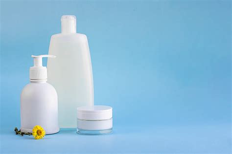 흰색 플라스틱 이랑 병 샴푸 또는 샤워 젤 디스펜서 크림에 대 한 유리 용기 치유 허브 Foalfoot 또는 투 실 고 파란 빛 푸른 빈 배경 복사 공간 0명에 대한 스톡