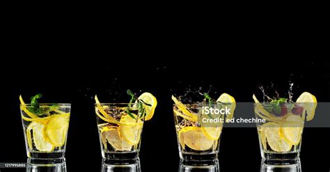 레몬과 민트와 레모네이드 또는 모히토 칵테일 4 잔 검은 배경에 차가운 음료 안경에 떨어지는 얼음을 튀기 공간을 복사하고 닫습니다 다발에 대한 스톡 사진 및 기타 이미지