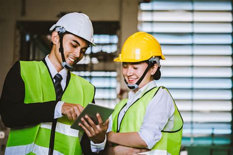 아시아 여성 엔지니어 공장 검사 와 남자 사업 들고 태블릿 컴퓨터 엔지니어 산업 우리는 헬멧 여성 작업 금속 작업 제어 산업에서 자동차 플라스틱 공장에서 공학에 대한 스톡