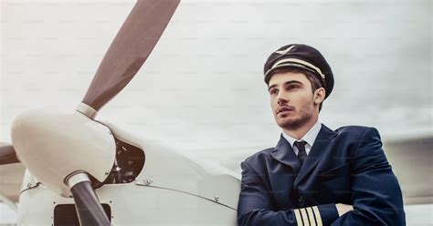 제복을 입은 젊은 잘 생긴 남자 조종사가 작은 개인 비행기 근처에 서 있습니다 사진 Unsplash의 고정된 이미지