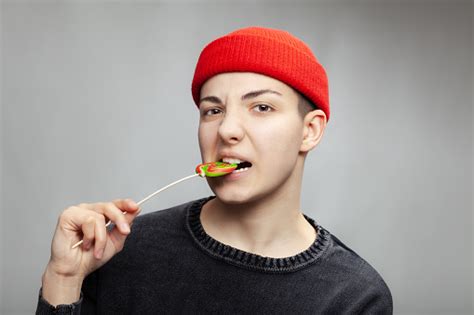 짧은 머리와 회색 배경에 블라우스와 빨간 모자를 쓴 롤리팝을 가진 소녀 20 24세에 대한 스톡 사진 및 기타 이미지 20 24세 20 29세 가지 식물 부위