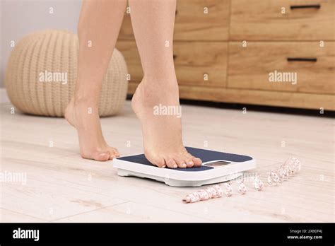 Woman Stepping On Floor Scale And Measuring Tape At Home Closeup Weight Control Stock Photo