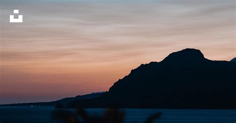 산은 물 위의 일몰을 배경으로 실루엣을 이룹니다 사진 Unsplash의 무료 파랑 이미지