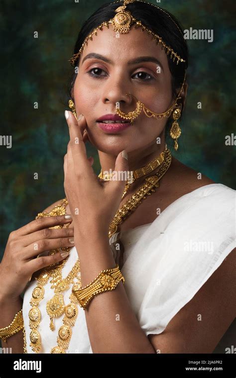 Indian Female Model Wearing A White Saree And Gold Jewellry Sporting A